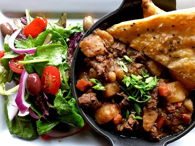 Cast iron comfort food at its finest—this hearty stew with a side salad and pastry topper is Delaware's answer to a warm blanket on a chilly day.