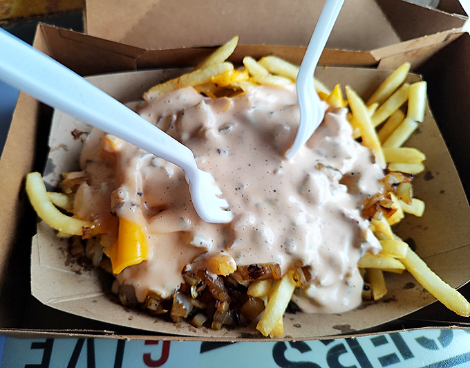 These aren't just fries—they're a canvas for chili, cheese, and thousand island artistry. The plastic fork is adorably optimistic given the delicious mess you're about to make.