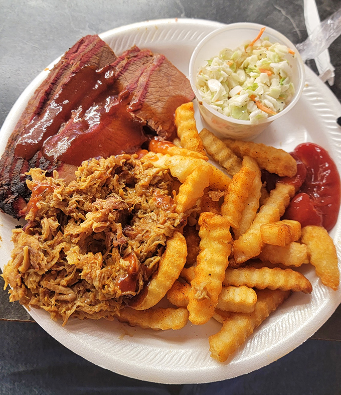 The BBQ trinity on one plate: pulled pork, brisket, and those crinkle-cut fries that somehow taste better than any others.