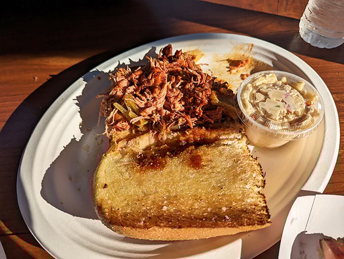 This pulled pork sandwich isn't just food – it's architecture. A masterpiece of smoke-kissed pork piled high on toasted garlic bread with creamy coleslaw.
