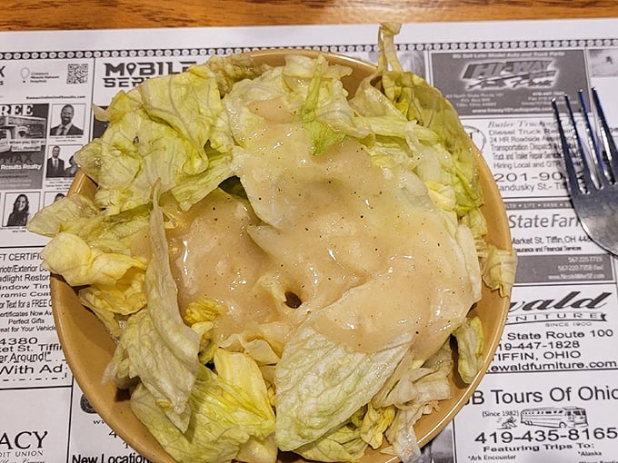 A simple salad served on newspaper – because when your main dishes are this legendary, even the sides come with a story.