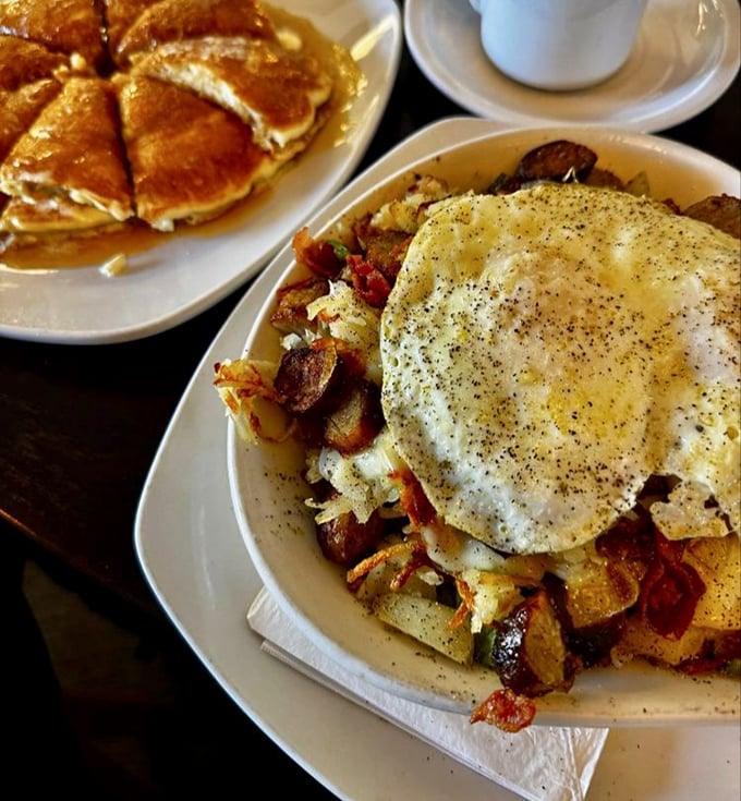 Breakfast potatoes topped with a sunny-side egg—proof that sometimes the simplest combinations create the most profound satisfaction. Pancakes lurk temptingly in the background.
