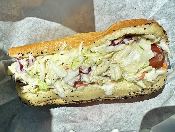 The slaw dog offers a cool, creamy counterpoint to the savory sausage beneath – like finding shade on a hot Florida afternoon.