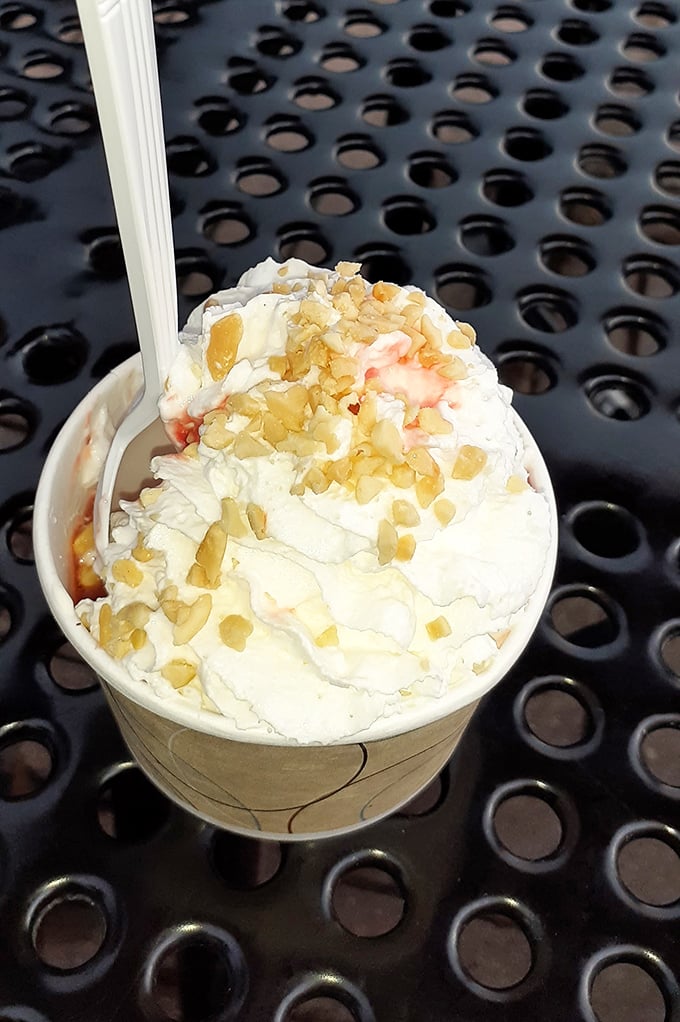 A mountain of soft-serve crowned with strawberry sauce and nuts—the kind of sundae that makes adults forget their dignity and dive in like eight-year-olds.