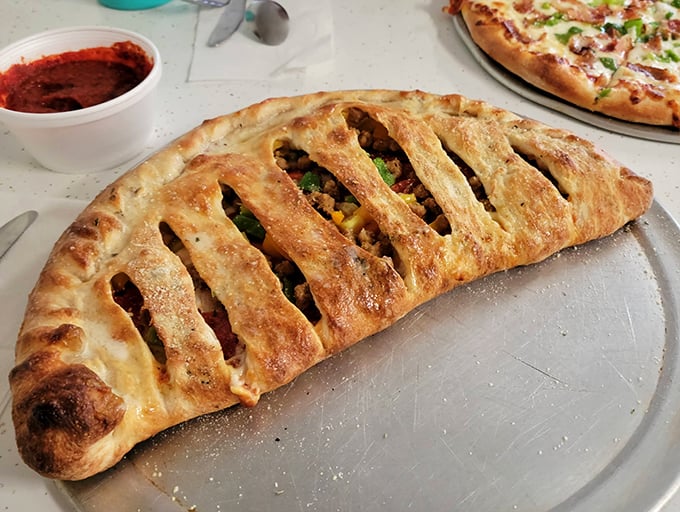 The stromboli arrives like an edible art piece—a golden-brown pastry revealing savory treasures with each steam-releasing cut.