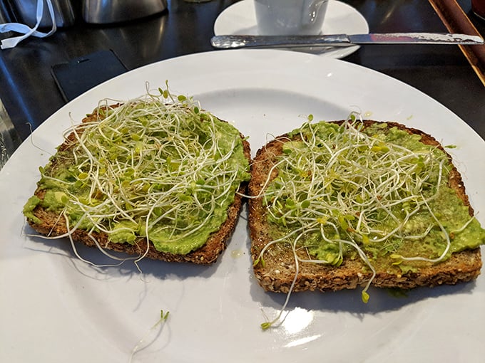 Avocado toast that Instagram was invented for—where creamy green goodness meets delicate sprouts on hearty bread. Simple ingredients, executed brilliantly.