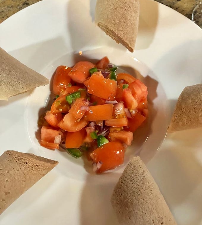 Tomato Fitfit surrounded by injera—a refreshing salad that proves Ethiopia mastered the "deconstructed" concept long before it became trendy in American restaurants.