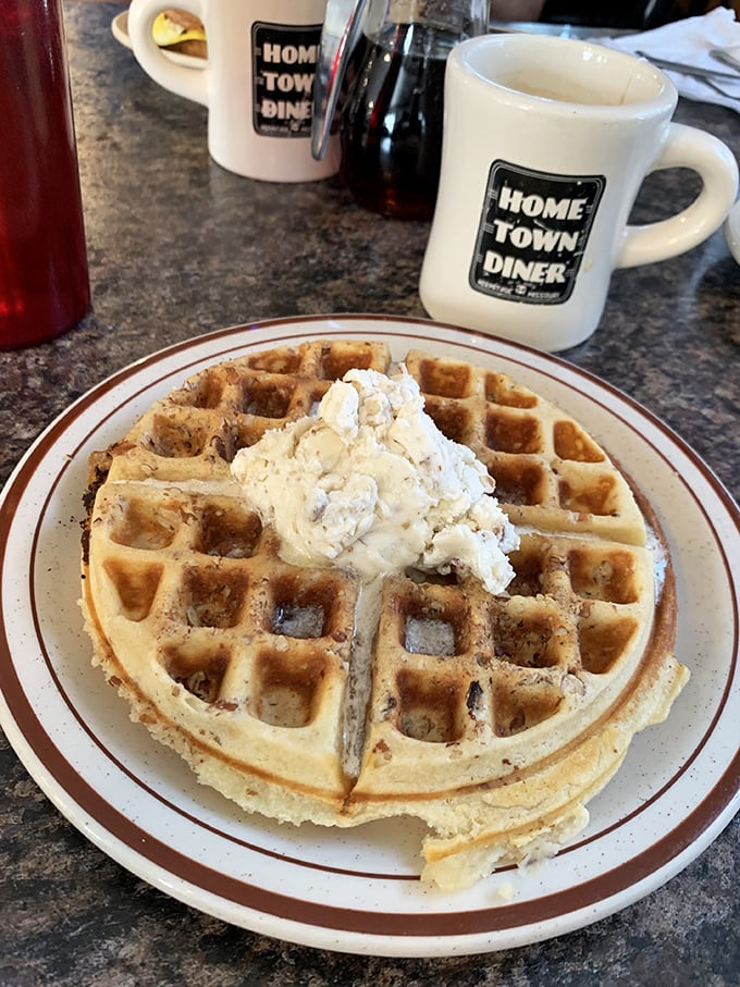 A perfect waffle crowned with a dollop of butter – served on the diner's signature plate with their branded mug standing guard nearby.