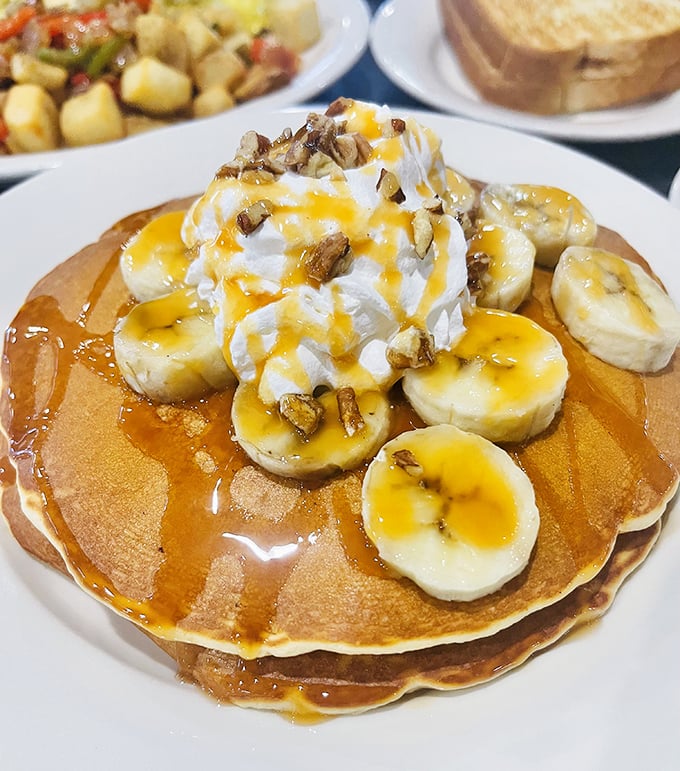 Pancakes topped with bananas, whipped cream, and nuts—because sometimes breakfast should feel like getting away with having dessert at 9 AM.