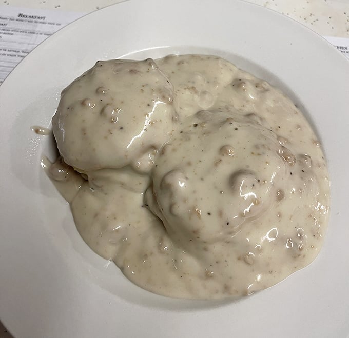 Biscuits and gravy that don't just sit on the plate—they embrace it, a creamy, peppery blanket that's worth every single calorie.