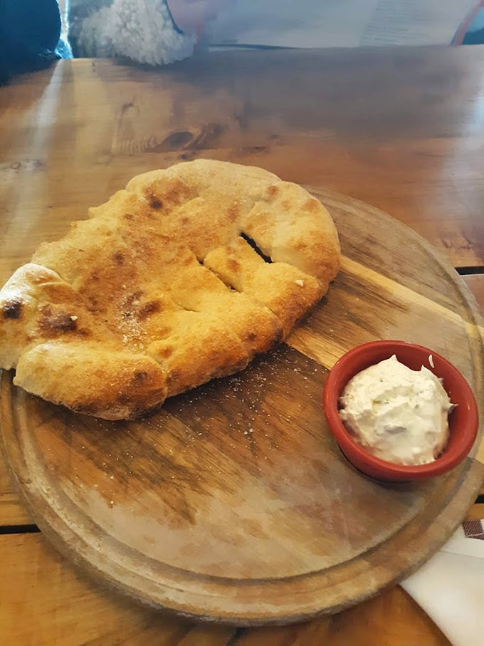 Fresh-baked flatbread with a side of creamy spread—proof that even the simplest starters at Woodshop deserve your full attention.