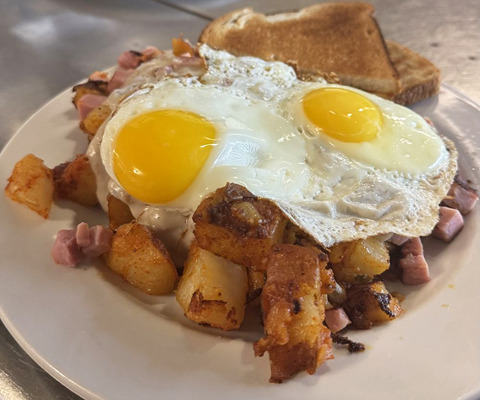 Two sunny-side-up eggs crowning a kingdom of potatoes and ham—breakfast royalty that doesn't require formal attire.