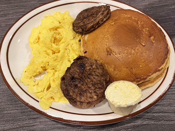 The breakfast trinity: fluffy pancake, scrambled eggs, and sausage patties. Simple pleasures that remind you why diners remain America's breakfast sanctuary.