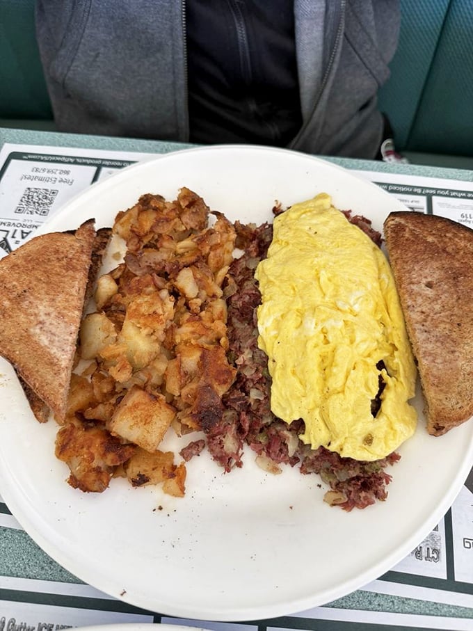 The holy trinity of breakfast: golden home fries, corned beef hash, and a folded omelet. Add toast for structural support and you've got architectural perfection.