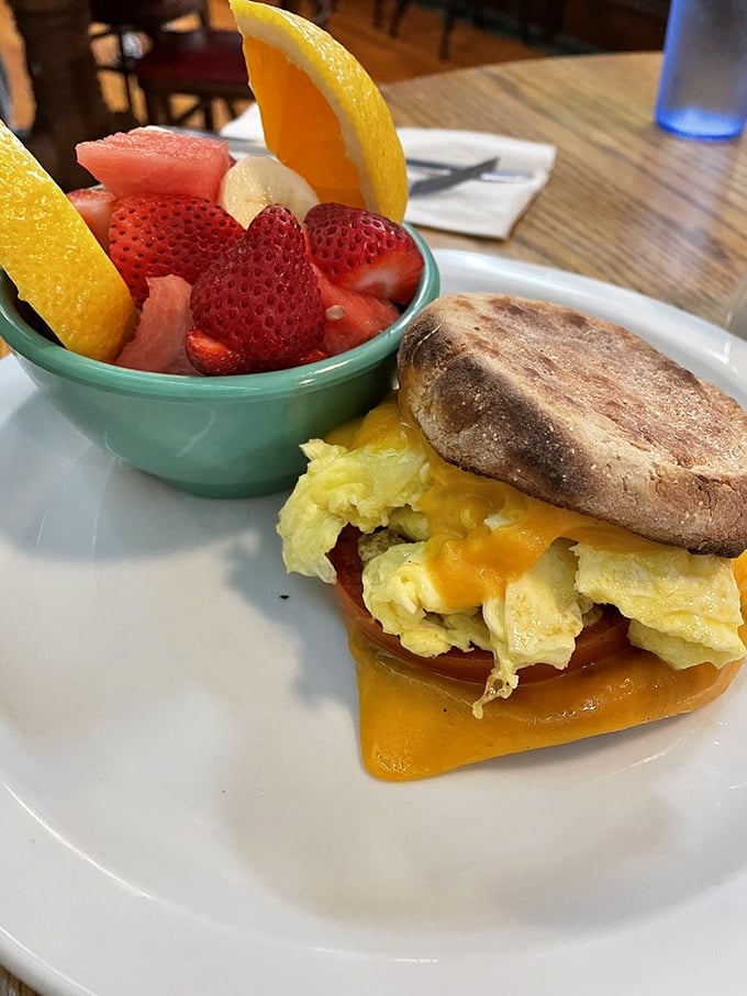The breakfast sandwich and fresh fruit bowl—proof that sometimes the simplest combinations create the most profound happiness.