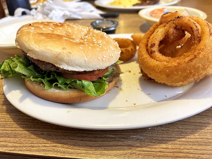A burger that requires a game plan before the first bite, paired with onion rings the size of bracelets. This is lunch that demands a nap afterward.