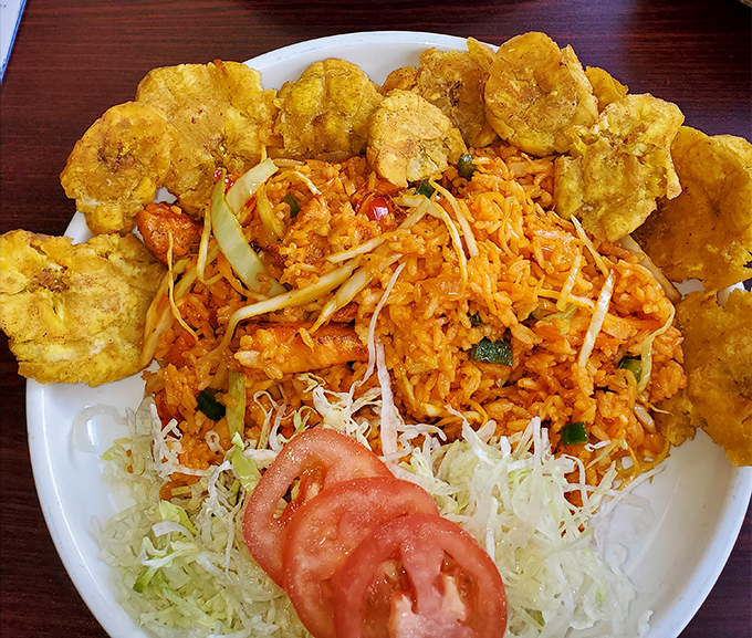 A fiesta on a plate! Vibrant yellow rice surrounded by perfectly fried plantains, with fresh tomatoes adding a pop of color that screams "vacation vibes."