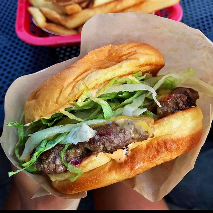 The burger in its natural habitat – wrapped in paper, ready for its close-up. That cheese drape should win awards for supporting role in a culinary drama.