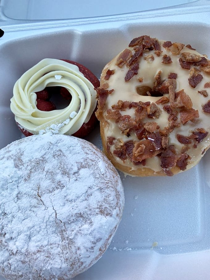 Decision paralysis has never been so delicious. Each donut in this trio tells a different story—powdered sugar poetry, bacon brilliance, and chocolate decadence.