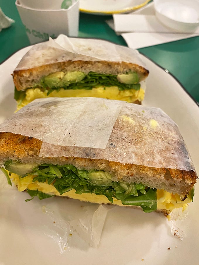 Sunshine on a plate—fluffy eggs, vibrant greens, and creamy avocado nestled between bread that's been toasted to golden perfection.