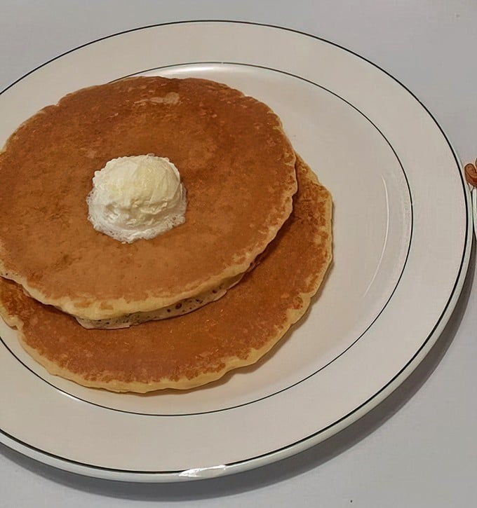 Pancakes so perfectly golden they look like they were painted by Norman Rockwell himself, crowned with a melting pat of butter just waiting for maple syrup's sweet embrace.