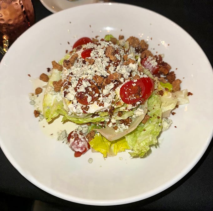 The wedge salad – that steakhouse classic – gets the Bare Bones treatment with fresh tomatoes, blue cheese crumbles, and bacon bits that refuse to be mere garnish.