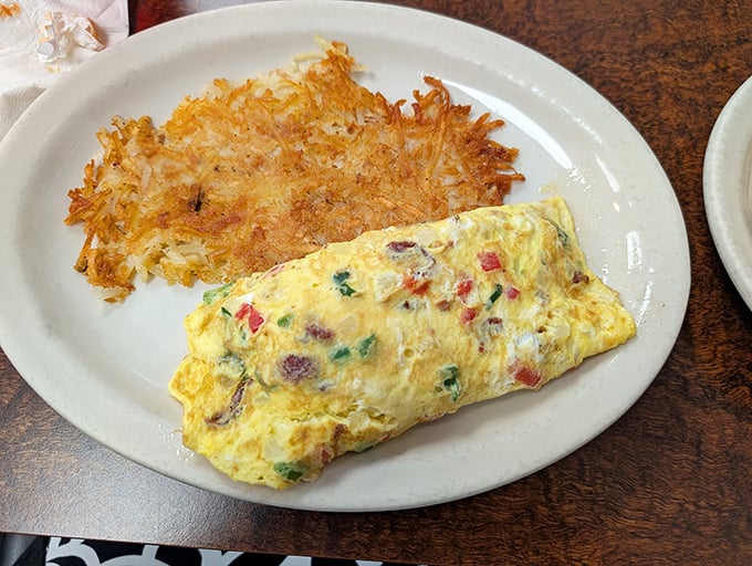 An omelet that's seen the world, packed with colorful vegetables and paired with hash browns crisped to golden perfection.