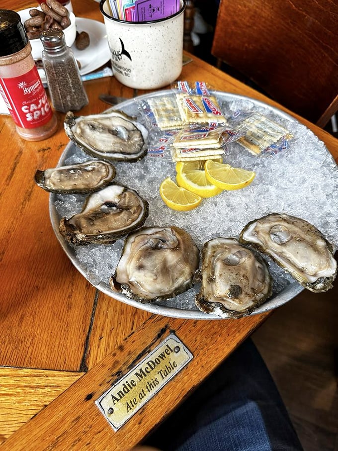 Raw oysters on ice with the table's brass nameplate visible—proof that celebrities and seafood lovers alike make pilgrimages to these briny treasures.