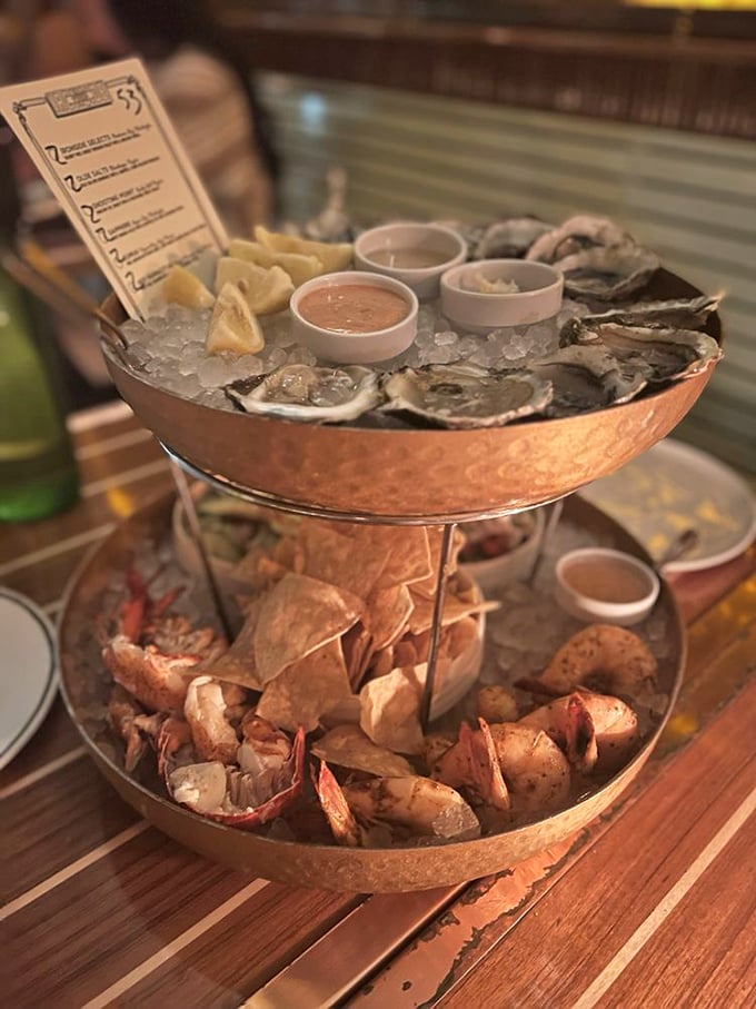 The seafood tower arrives like Neptune's own birthday cake—oysters on ice above, succulent shrimp below, happiness everywhere.