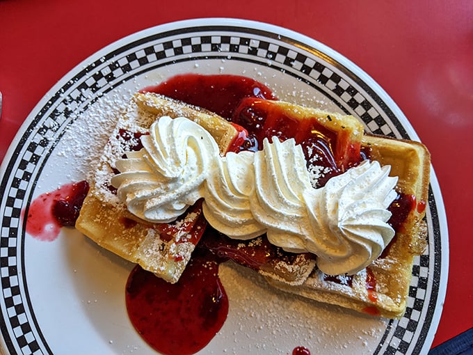 Breakfast dessert masquerading as a legitimate meal—waffles crowned with whipped cream and strawberry sauce that make Monday mornings bearable again.