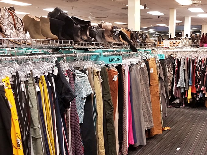 Above, rows of boots stand like stylish sentinels; below, racks of color and pattern line the path—thrift shopping’s version of a runway waiting for its star.
