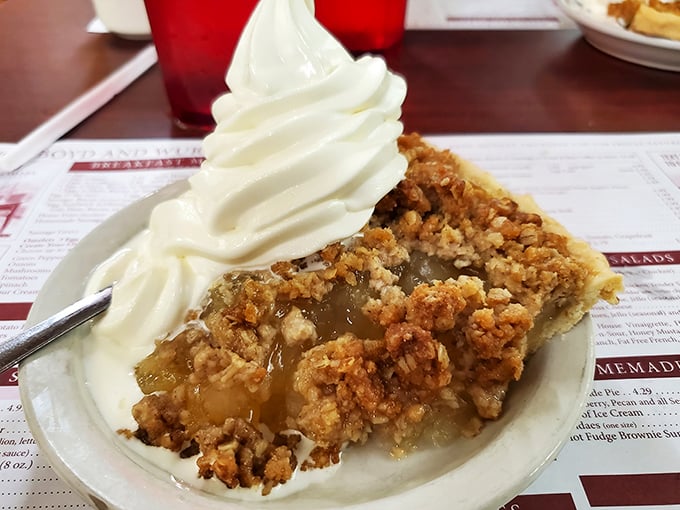Apple pie that's having an identity crisis as a crumble. That whipped cream isn't just a topping—it's the cloud you'll float away on.