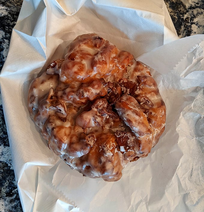This apple fritter isn't just a pastry; it's a topographical marvel of peaks and valleys, all glazed to glistening perfection.