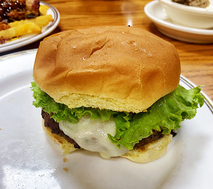A burger that requires both hands and several napkins—melted cheese draping over the patty like it's getting comfortable for a long stay.