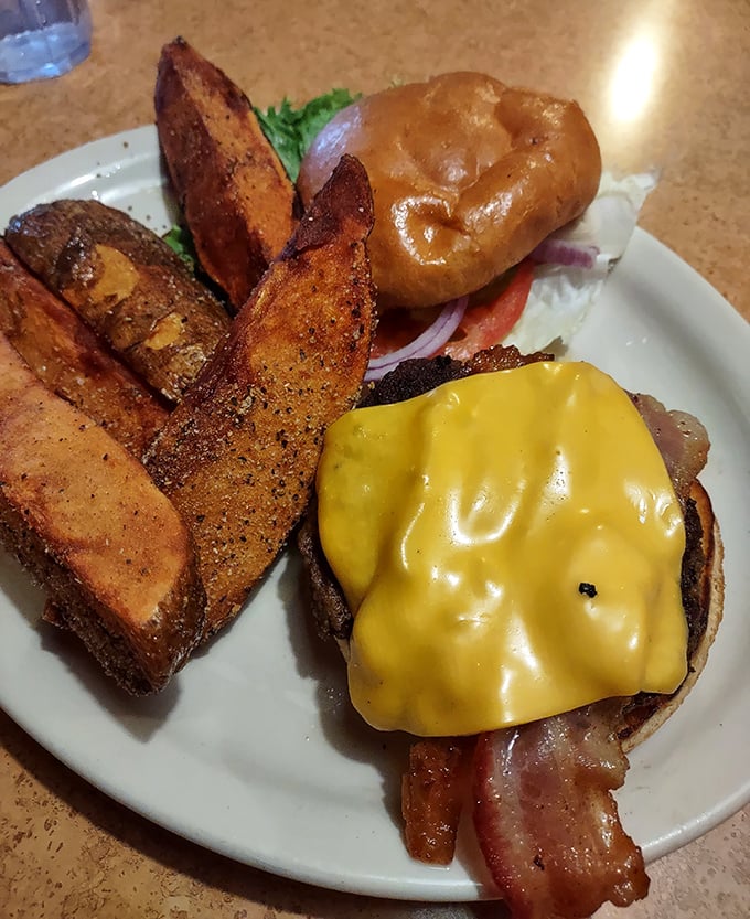 This isn't just a burger—it's architecture. Those potato wedges standing guard like delicious sentinels of crispiness deserve their own fan club.