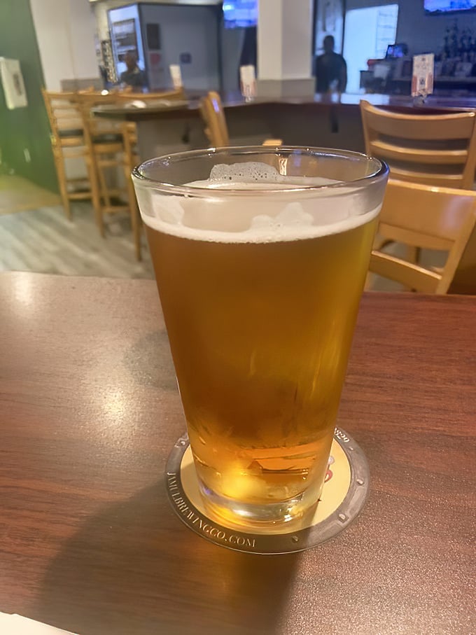 A cold beer in a proper glass—civilization's perfect answer to barbecue's primal appeal. The wood tables say "stay awhile."