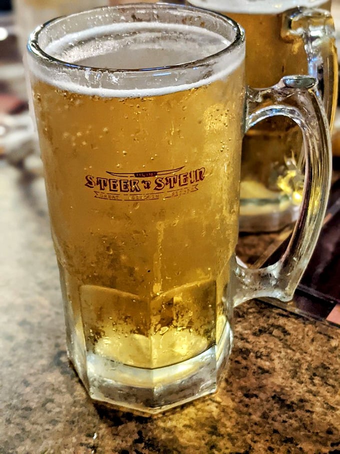 A frosty mug bearing the Steer N' Stein logo—because sometimes the perfect companion to a great steak is a cold beer in substantial glassware.