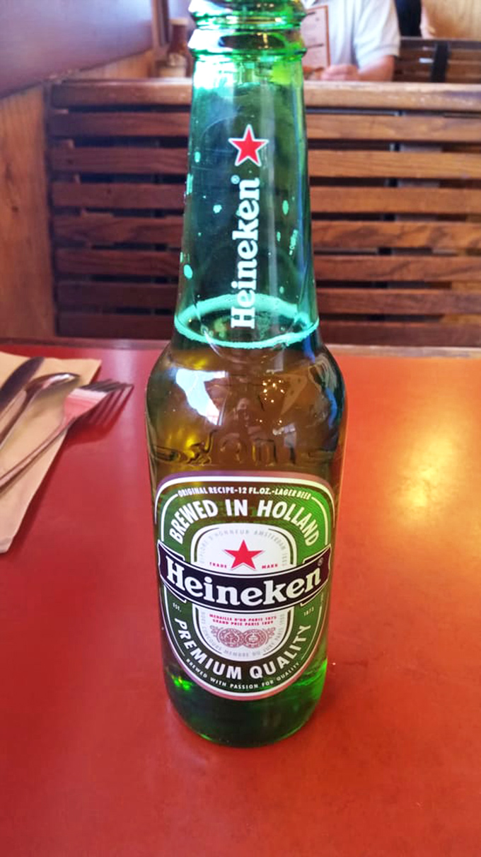 Nothing complements smoky BBQ quite like an ice-cold Heineken. The green bottle practically glows with promise against the rustic tabletop.