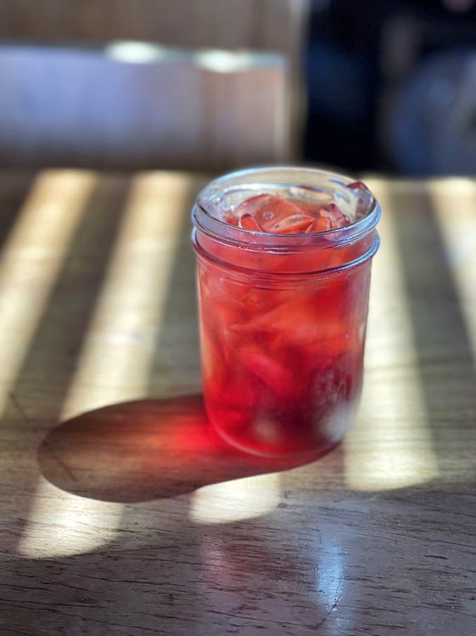 That ruby-red refreshment catching the sunlight isn't just a drink—it's the perfect palate cleanser between bites of oceanic bliss.