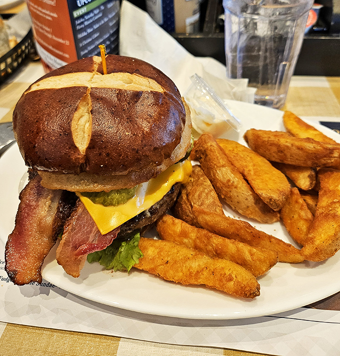 This isn't just a burger—it's a skyscraper of flavor on a pretzel bun with fries so perfectly golden they deserve their own Instagram account.