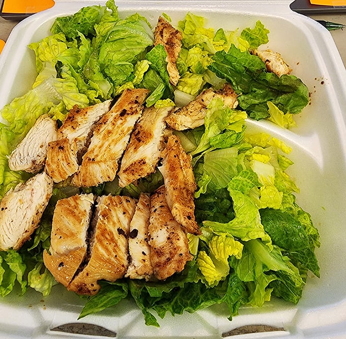 Fresh greens topped with perfectly grilled chicken – proof that not everything here will require a nap afterward.