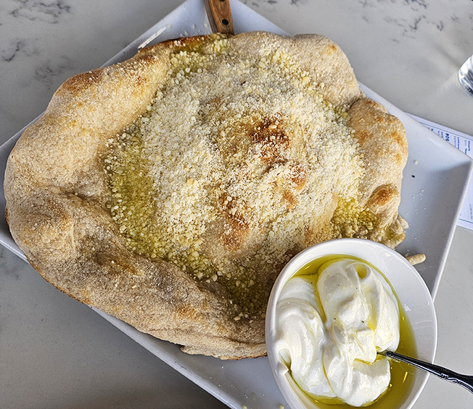 Not just bread – a pillowy cloud of dough transformed into a vessel for what appears to be the creamiest ricotta this side of Naples.
