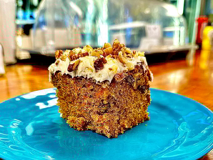 This carrot cake isn't just dessert—it's an event. That cream cheese frosting and those candied nuts are performing a beautiful duet on a turquoise stage. 