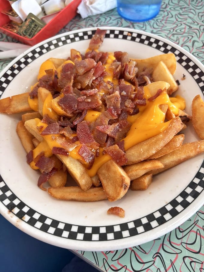 Cheese fries with bacon bits—the dish that nutritionists hate and your soul absolutely loves. Diet culture's kryptonite, served on the diner's signature checkered plates.