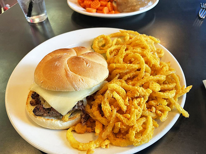 A cheeseburger and onion rings that remind you why simple food, done right, will always trump pretentious culinary trends. American poetry on a plate.