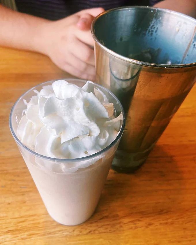 The milkshake and water glass pairing—one for immediate pleasure, one for the guilt that follows. A perfect yin and yang of diner dining.