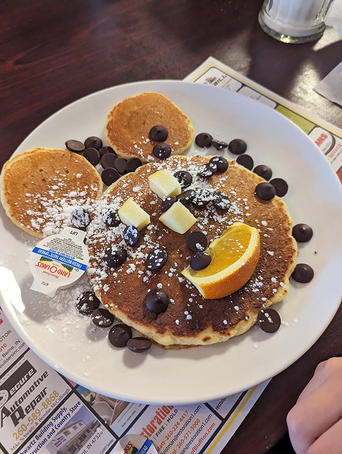 Mickey Mouse never looked so delicious—chocolate chip pancakes dusted with powdered sugar and a smile made of butter and fruit.
