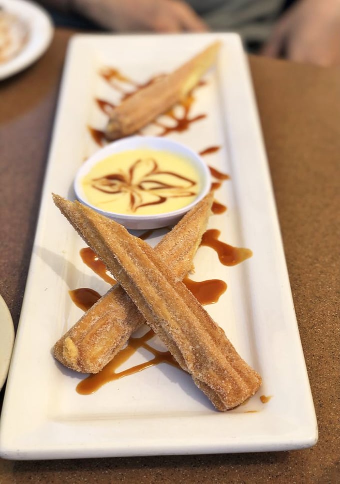 Churros arranged like edible Lincoln Logs of happiness. That caramel drizzle isn't just for show—it's the finishing touch on cinnamon-sugar perfection.