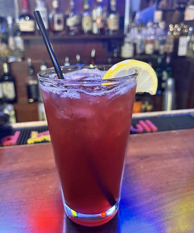 In a world of complicated cocktails with names longer than novels, this ruby-red beauty with a lemon slice is refreshingly straightforward.
