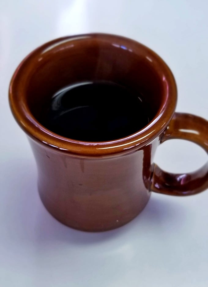 The humble brown mug holds coffee that doesn't need fancy Italian names or artisanal foam—just honest caffeine that gets the job done.